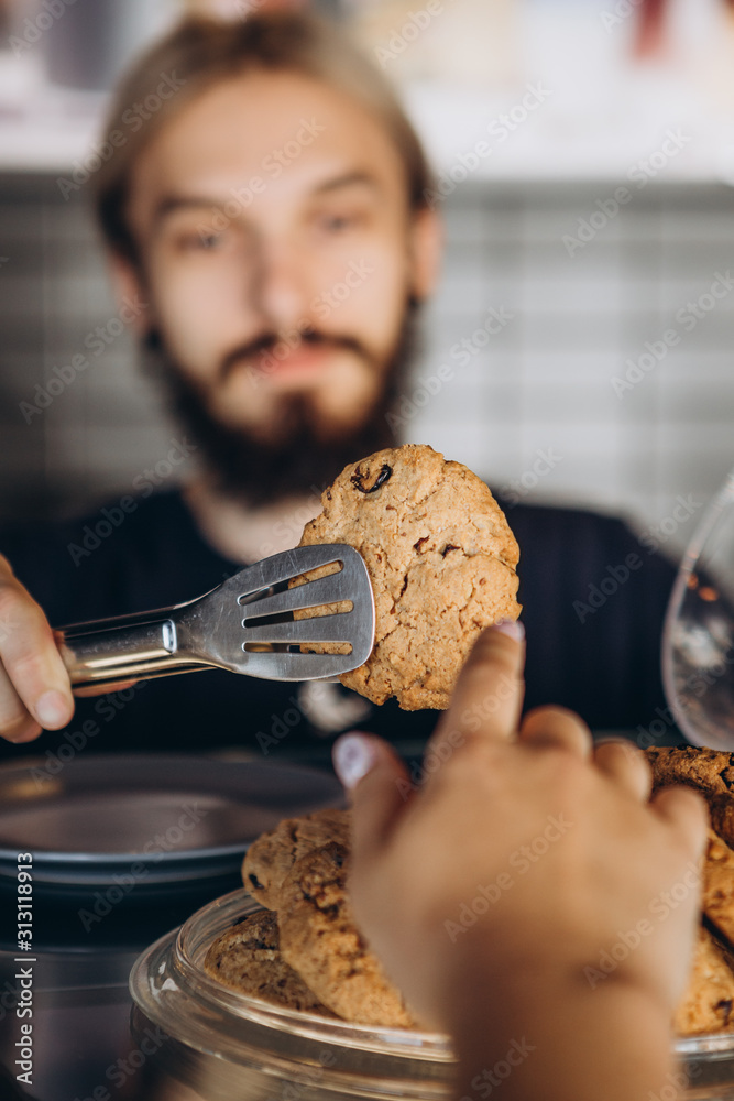 Young male confectioner working at his coffee shop, selling cookies to ...
