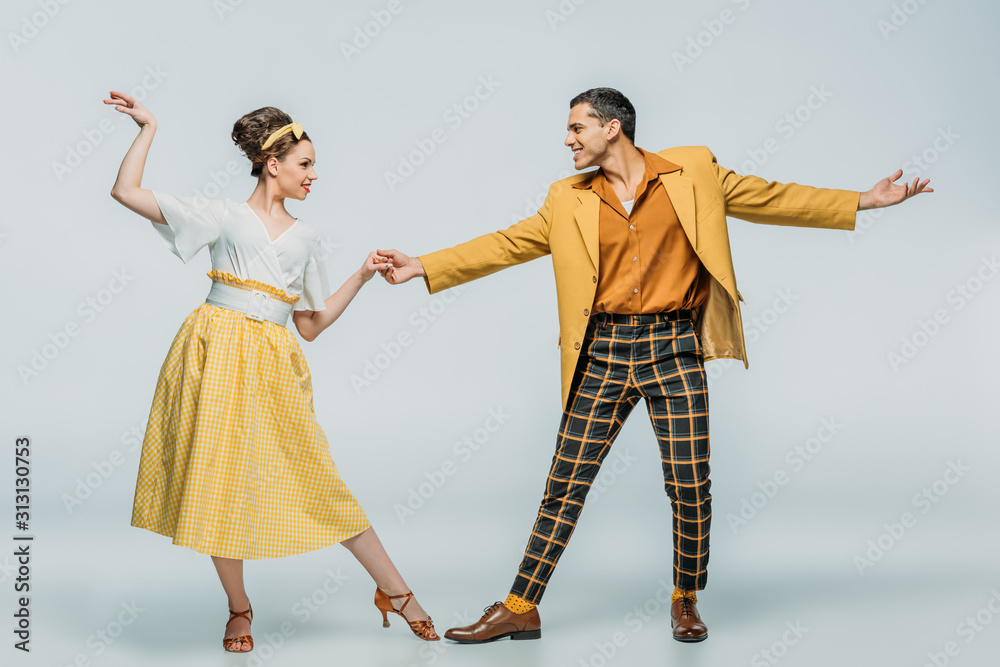 Stylish dancers holding hands while dancing boogie-woogie on grey ...