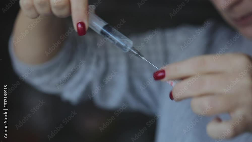 Middle-aged woman picking up medication into a syringe and prepares it ...