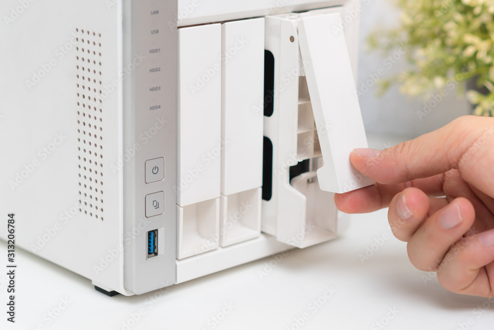 Fotka „Closeup, a man’s hand open one of drives arrays of personal NAS ...
