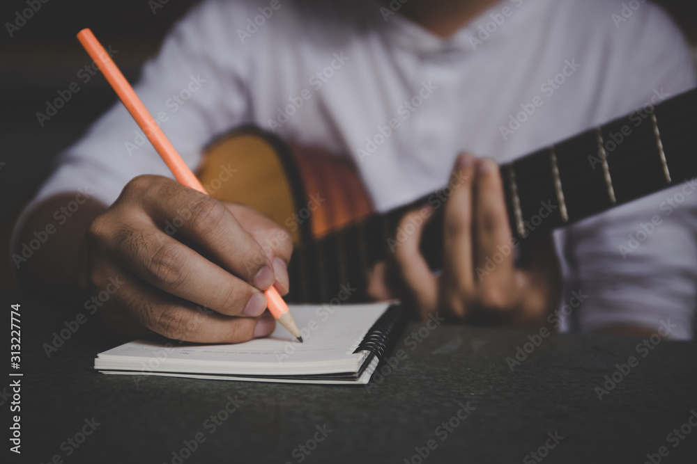 songwriter thinking and writing notes,lyrics in book at studio.man ...