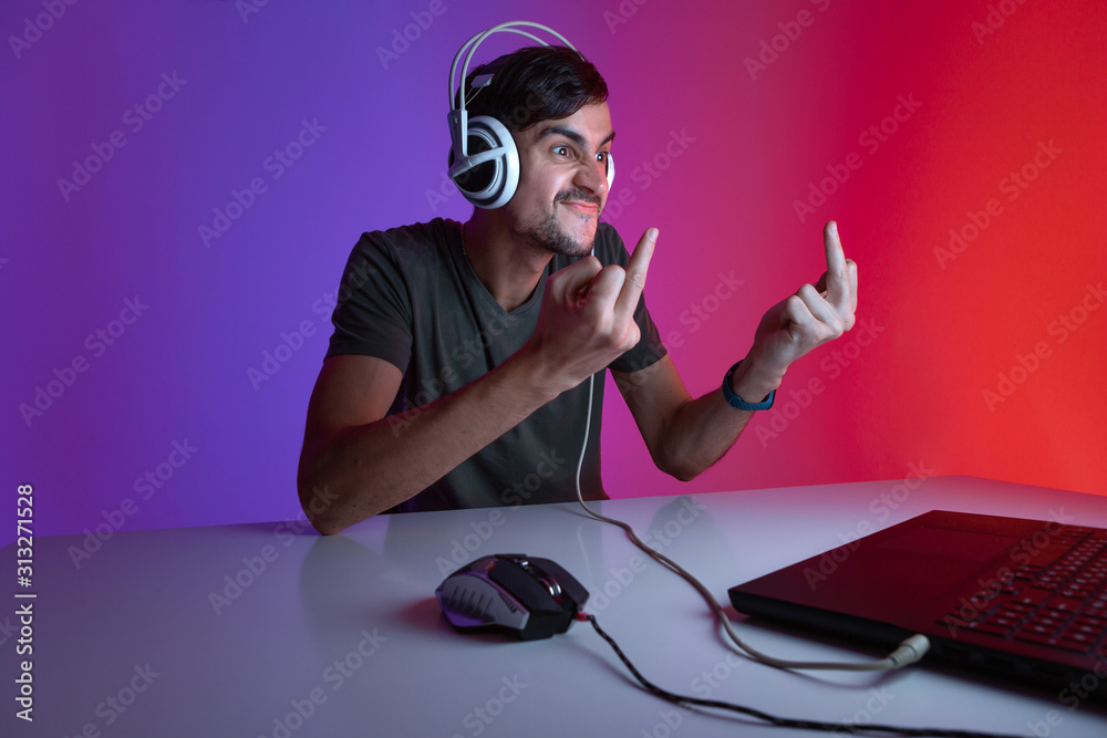 Portrait of an angry gamer playing video games on computer in dark room ...
