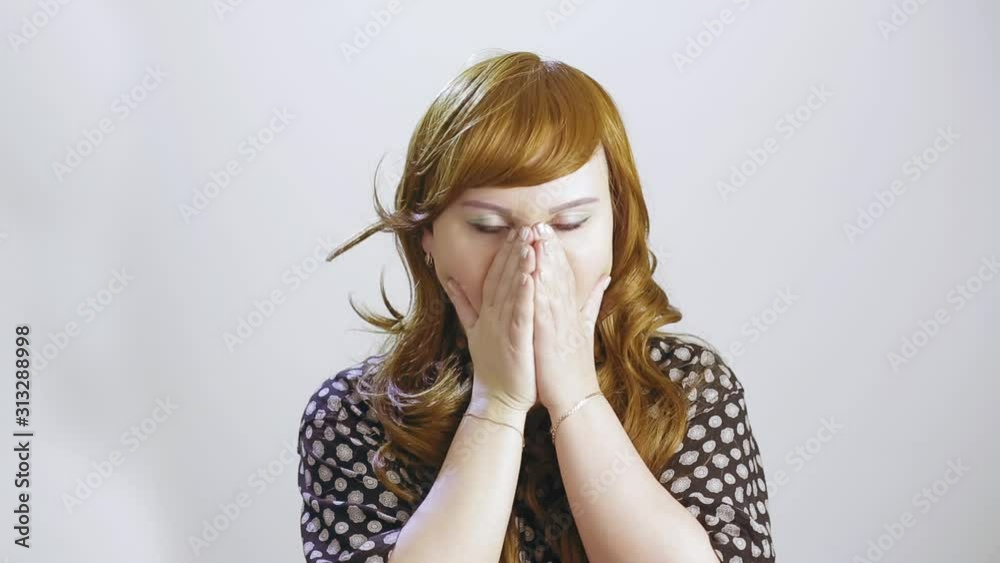 Young woman on a white background shows an emotion of shame. The ...