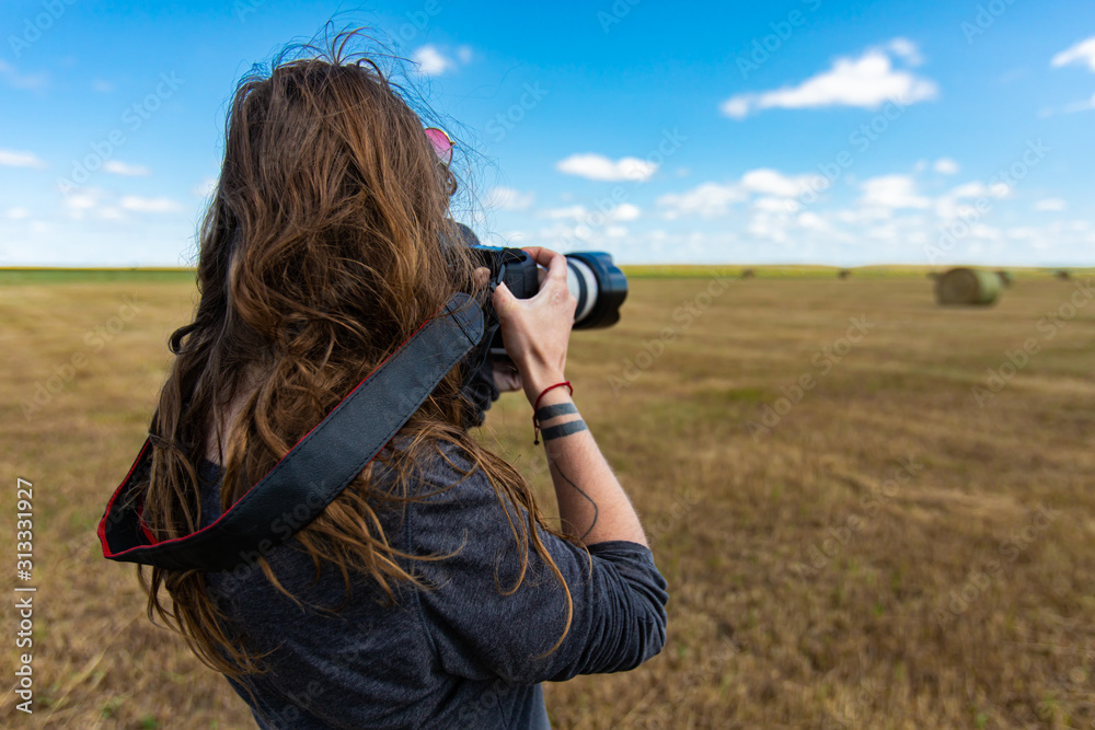 Young female photographer with long hair, viewed from behind, pictures ...