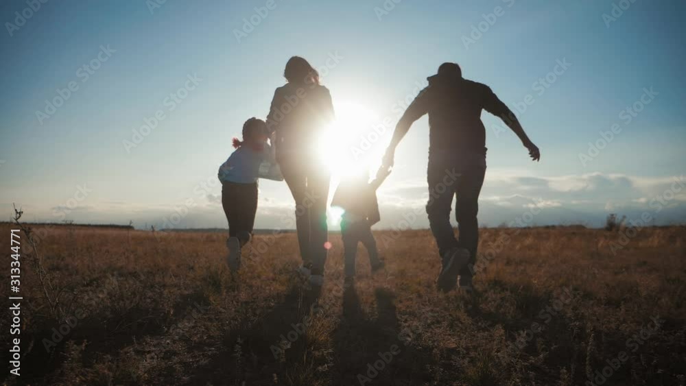 Happy young family together with children at sunset. People silhouettes ...
