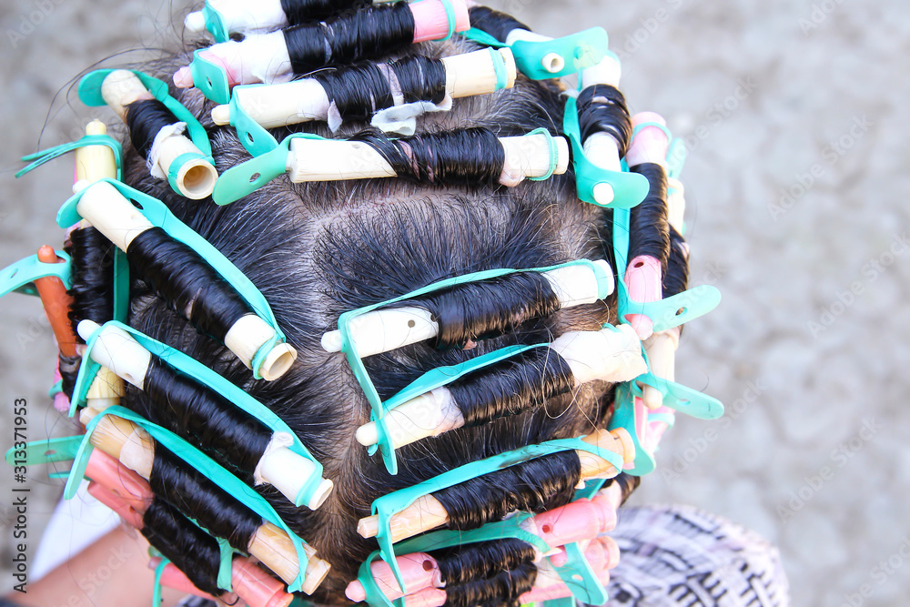 Elderly asian woman head and colorful plastic rollers with hair perm ...