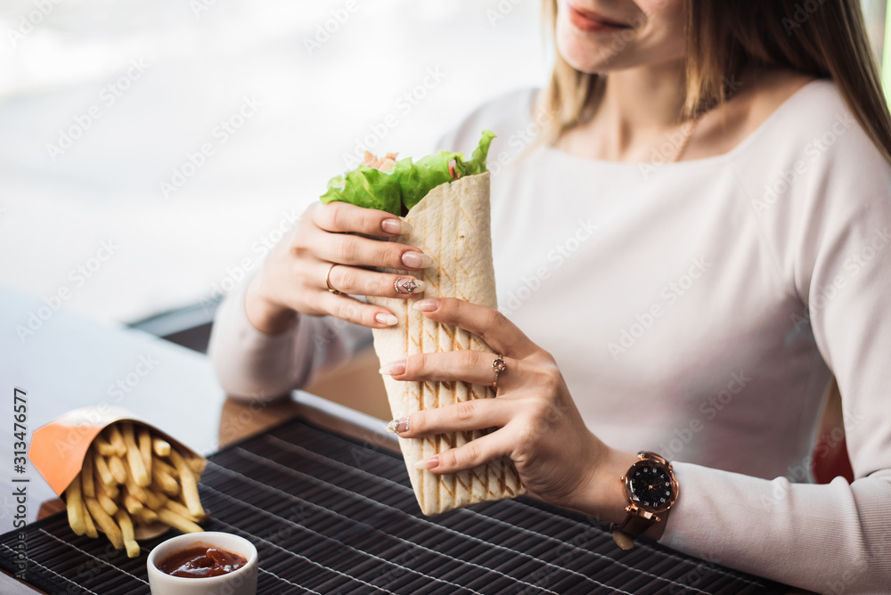 Shawarma, in the hands of a girl. The concept of fast food. Pretty ...