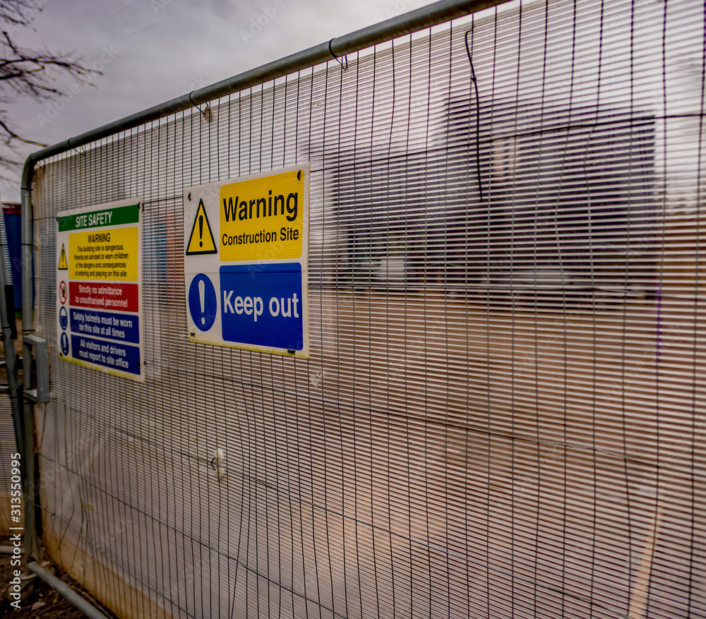 Building site entrance. Wire gate with warnings and permission signs ...