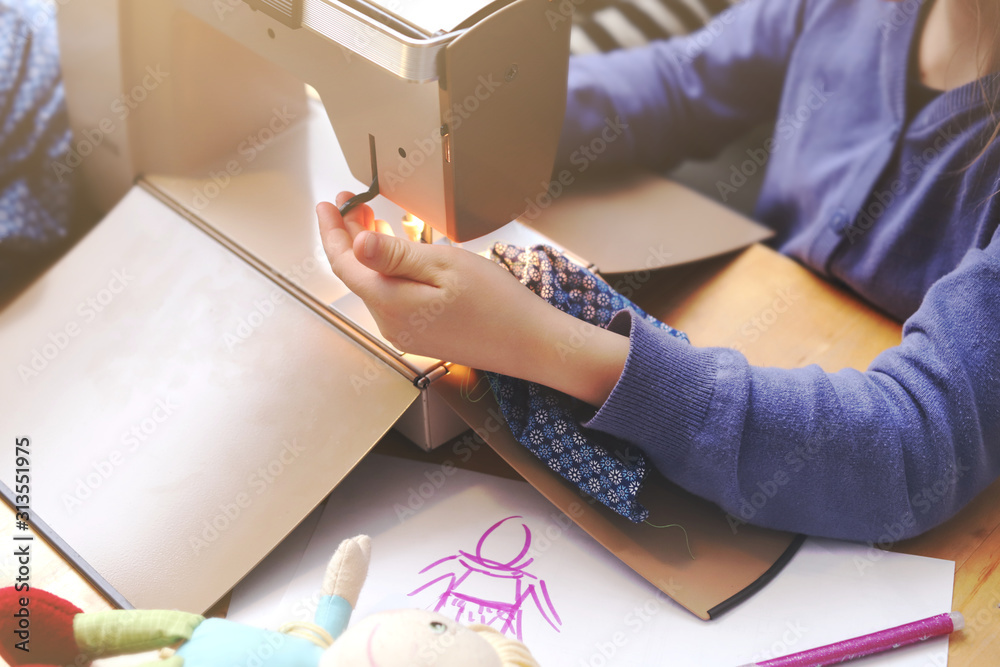 Enthusiastic young girl works with a compact sewing machine under ...