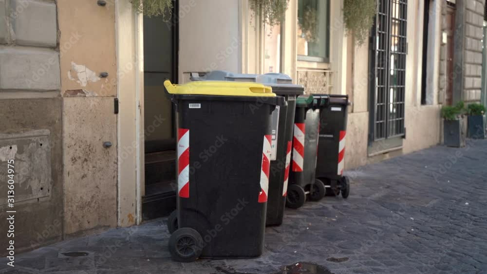Black plastic trash containers on the street in Rome. Garbage ...