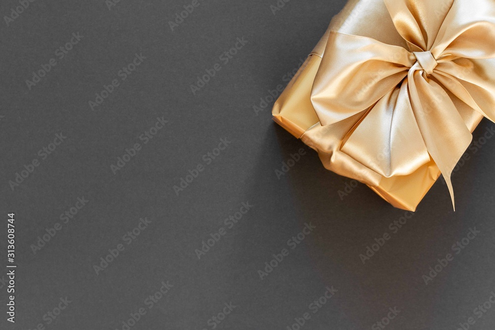 Festive background with gold gift, box with gold ribbon and bow on ...