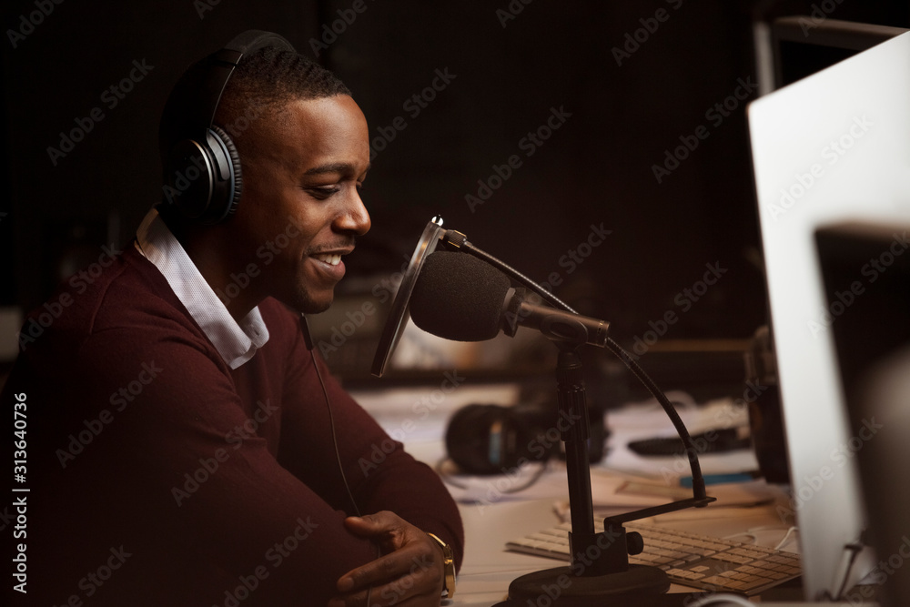 Side view of smiling businessman talking over microphone on desk in ...
