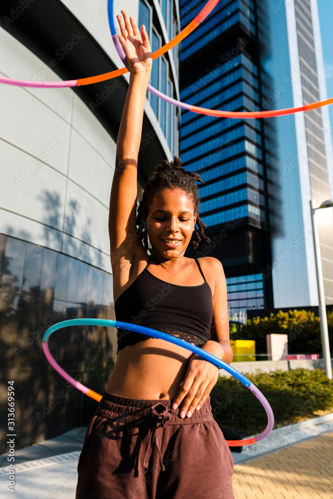 Generation Z woman performing Hula Hoop dance with rings in downtown ...
