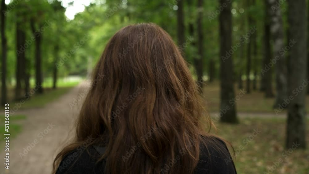 Gimbal shot of woman brunette hair back walking alone on the alley in ...