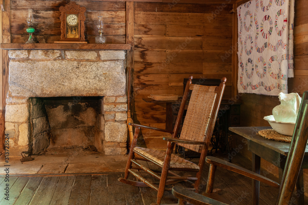 Interior of an old fashioned cabin with a wicker rocker and stone ...