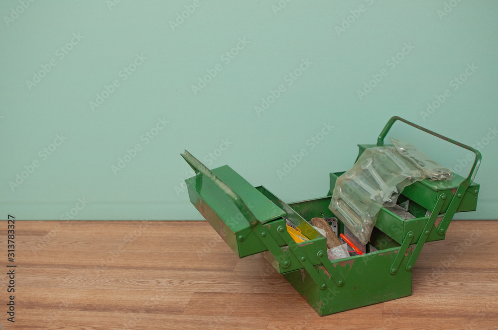 Green metal toolbox on a wooden floor with a green background. Closeup ...