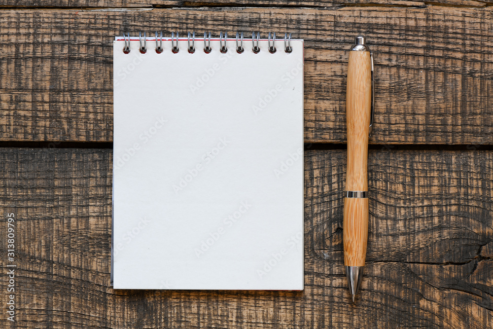 Empty white notebook and pen on the wooden table. Top view, high ...