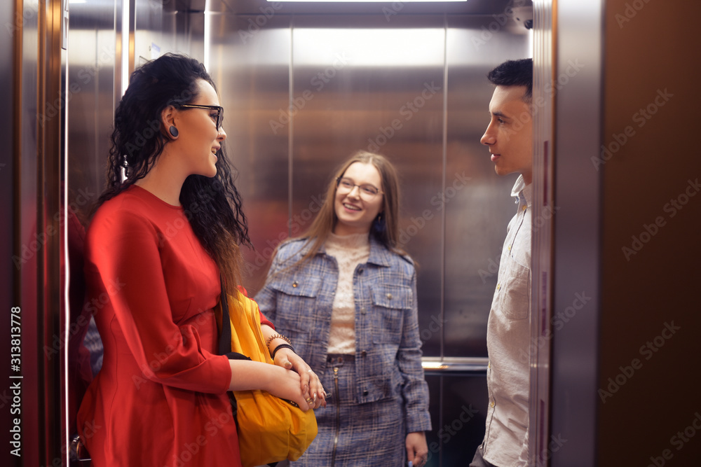 The girls and the guy ride in the elevator. Students in the elevator go ...