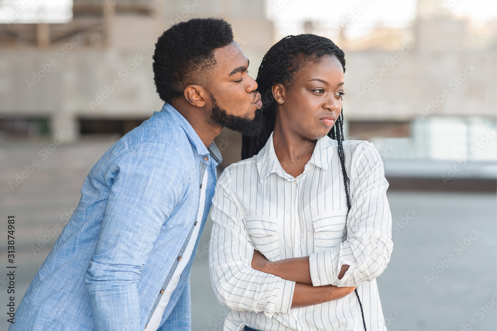 Displeased black girl rejecting kiss from annoying guy Stock Photo ...