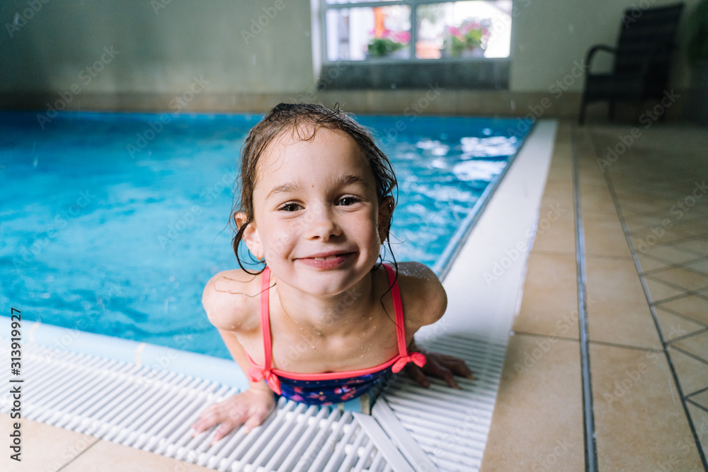 Portrait little girl having fun in indoor swimming-pool. The girl is ...