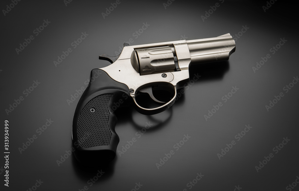 Silver pistol revolver on a black background. Low key photography ...