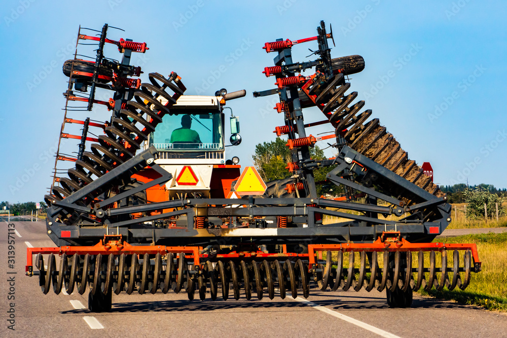 A farmer is seen driving a large industrial tractor from behind, with ...