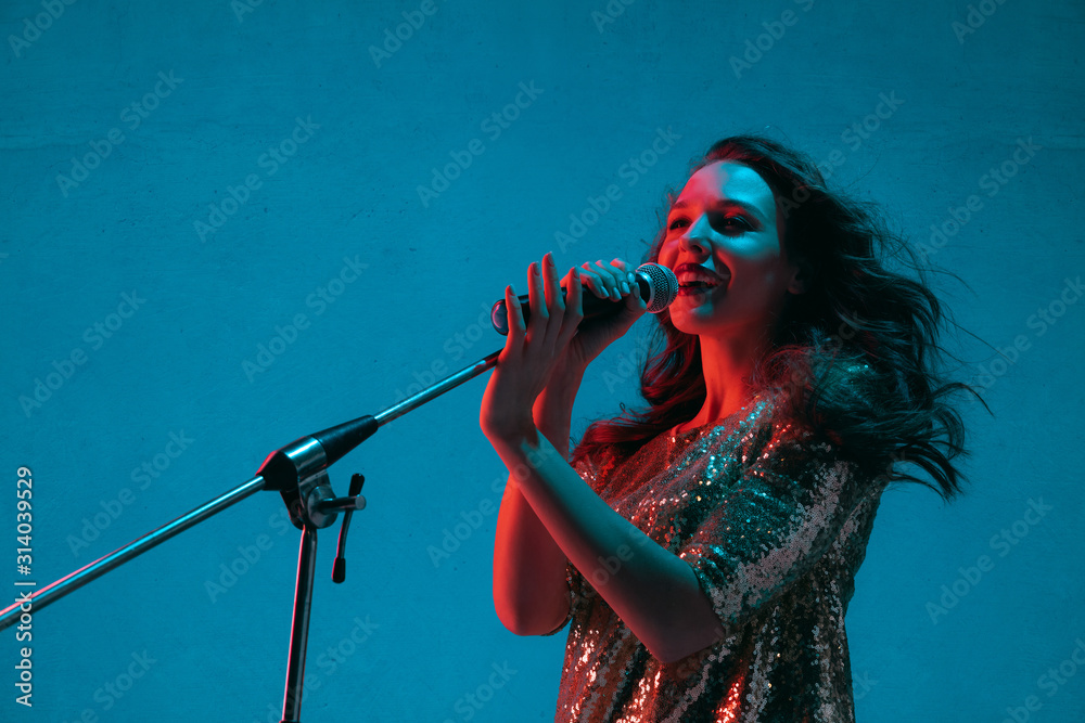 Caucasian female singer portrait isolated on blue studio background in ...