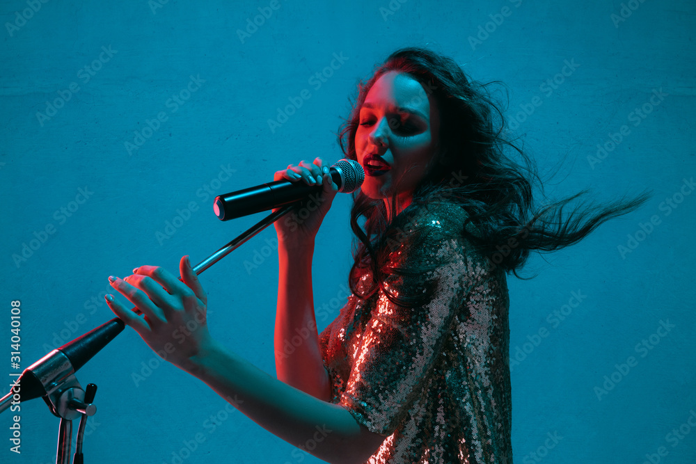 Caucasian female singer portrait isolated on blue studio background in ...
