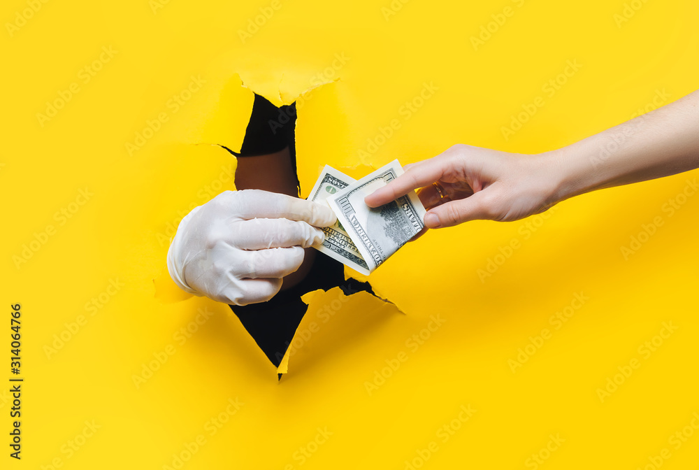 Hand of a woman patient gives money in the form of hundred-dollar bills ...
