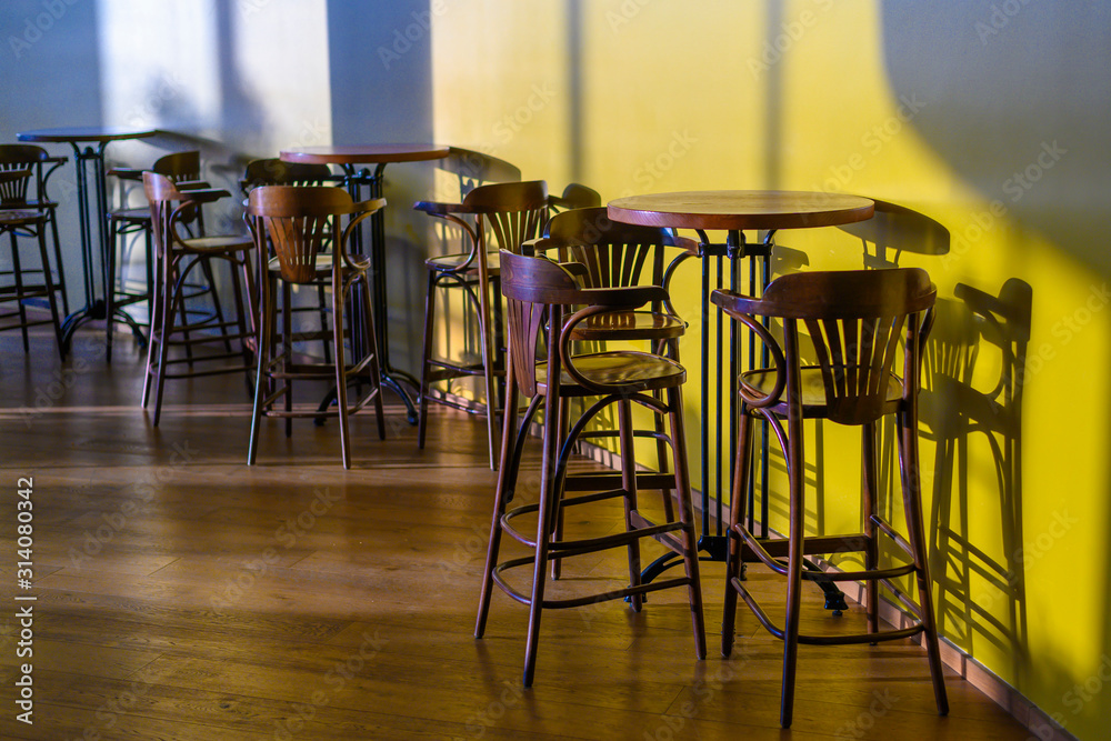 Tall antique wooden tables and chairs stand in a cafe, restaurant. A ...