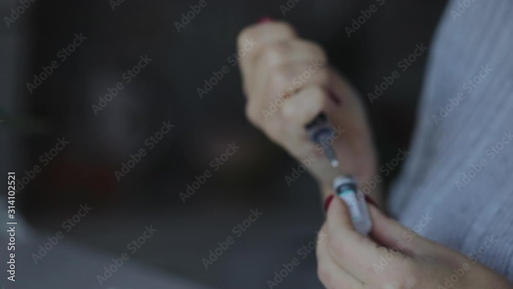 Girl picking up medication into a syringe and prepares it for injection ...