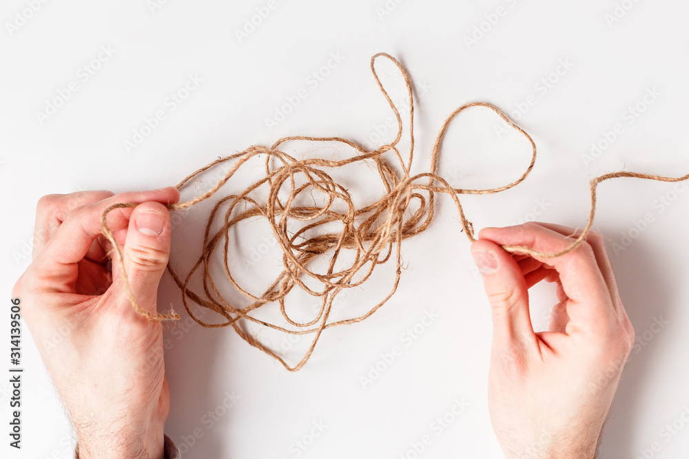 Man untangles a tangled thread. Top view isolated on a white background ...