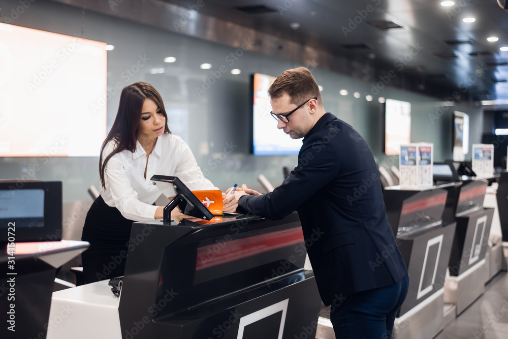 Side view of handsome man wearing glasses giving passport to staff at ...