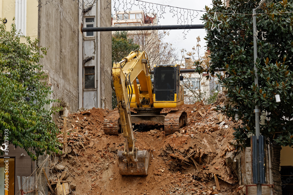 Excavator parked on debris of a ruined building after it collapsed. An ...