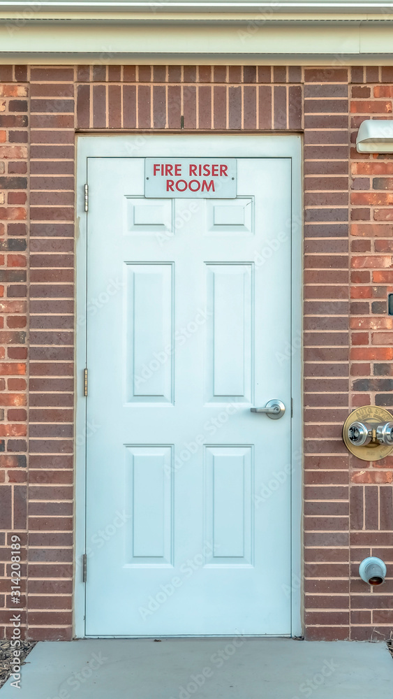 Vertical frame Fire Riser Room sign on the white wood door of a ...
