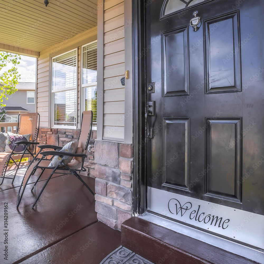 Square frame Front door of house with glass panes and porch with chairs ...