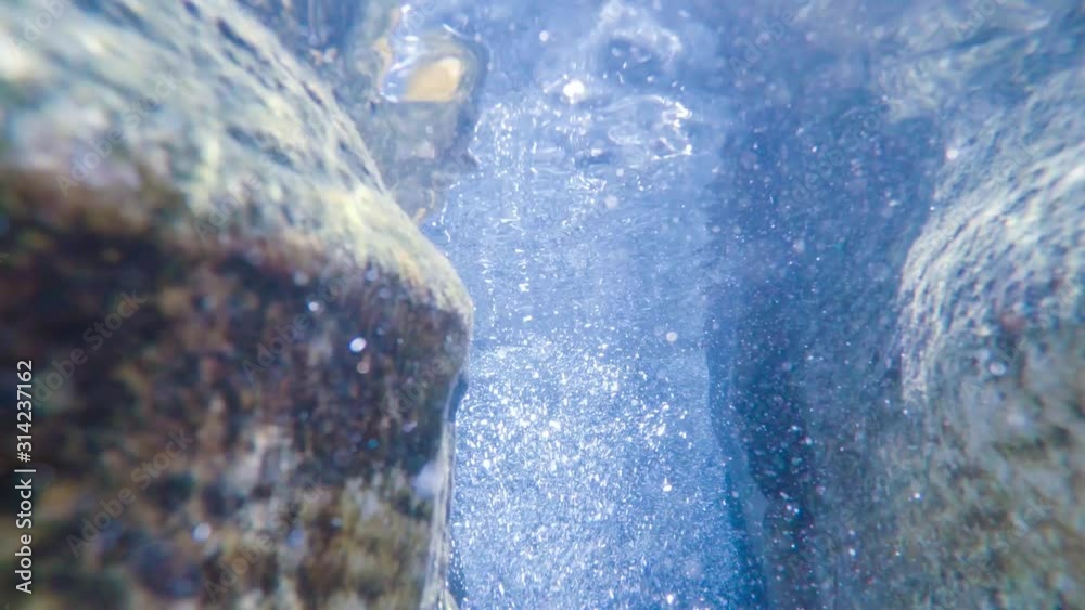 Underwater framing of a waterfall along a mountain stream from which ...