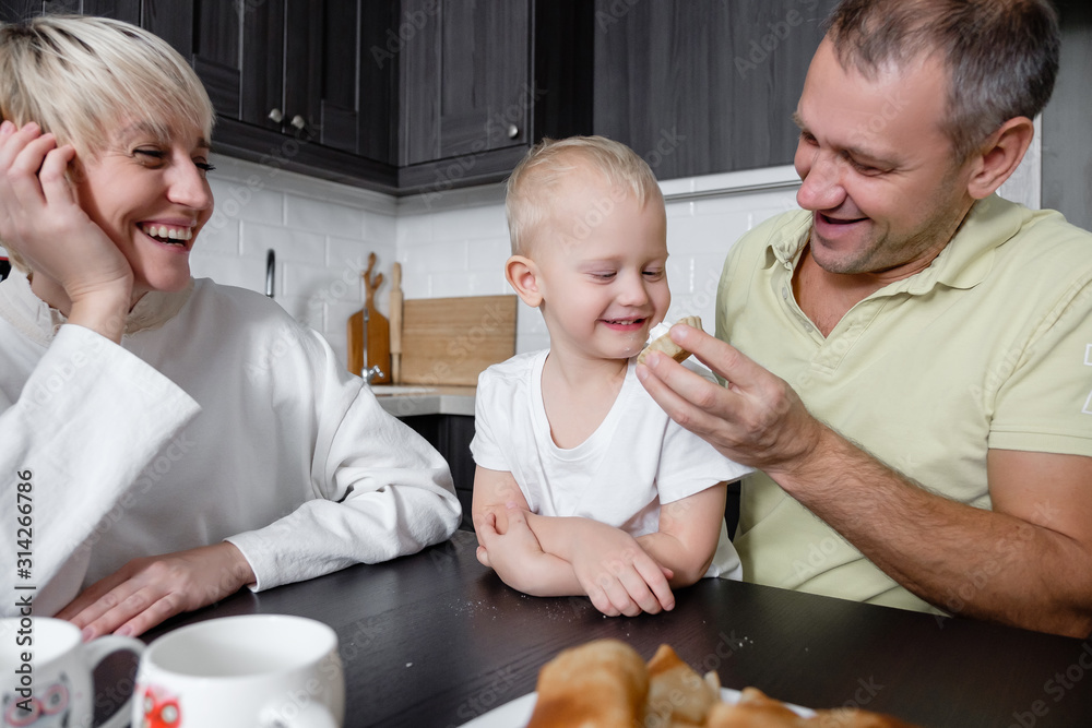 Happy kind smiling parents mom and dad feed their little son a cake ...