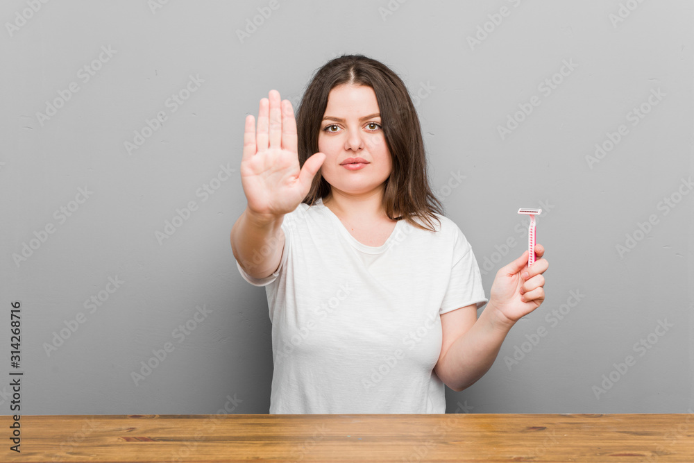 Young plus size curvy woman holding a razor blade standing with ...