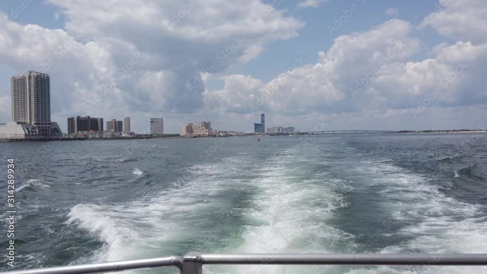 View from the back of a motor boat sailing in the ocean showing a wake ...
