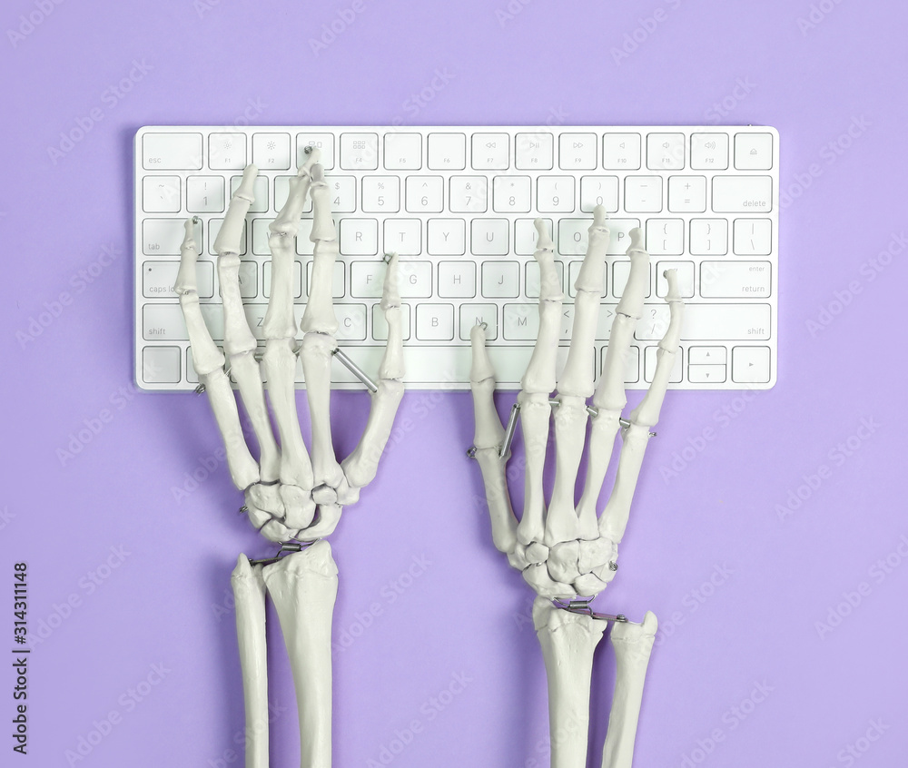 Human skeleton using computer keyboard on violet background, top view ...