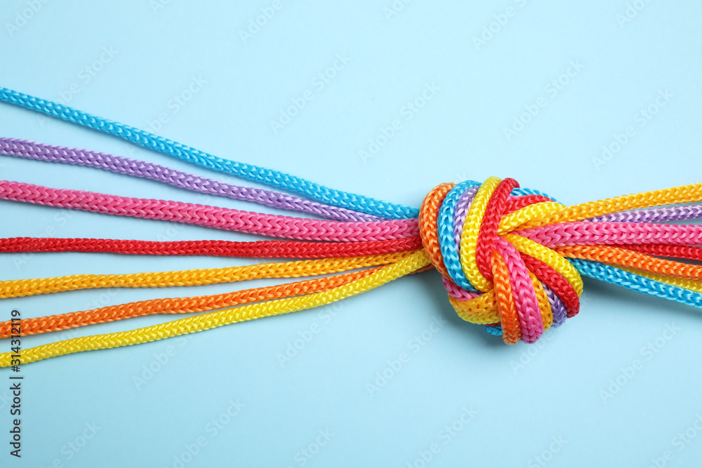 Colorful ropes tied together on light blue background, top view. Unity ...