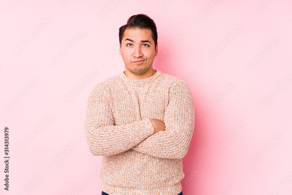 Young curvy man posing in a pink background isolated unhappy looking in ...