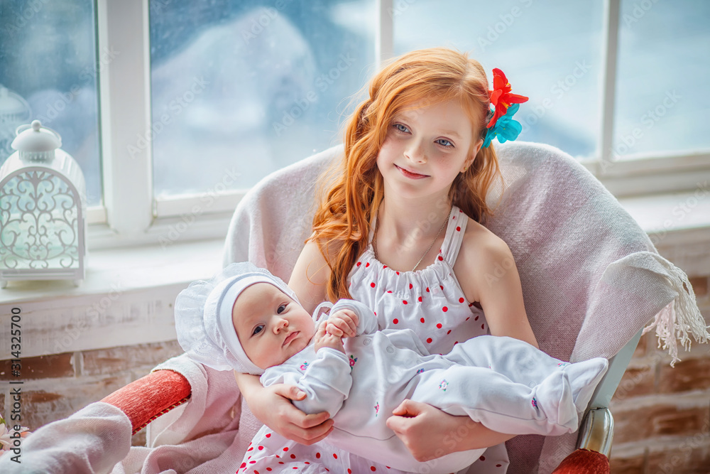 Charming pretty girl teenager holds in her arms her younger newborn ...