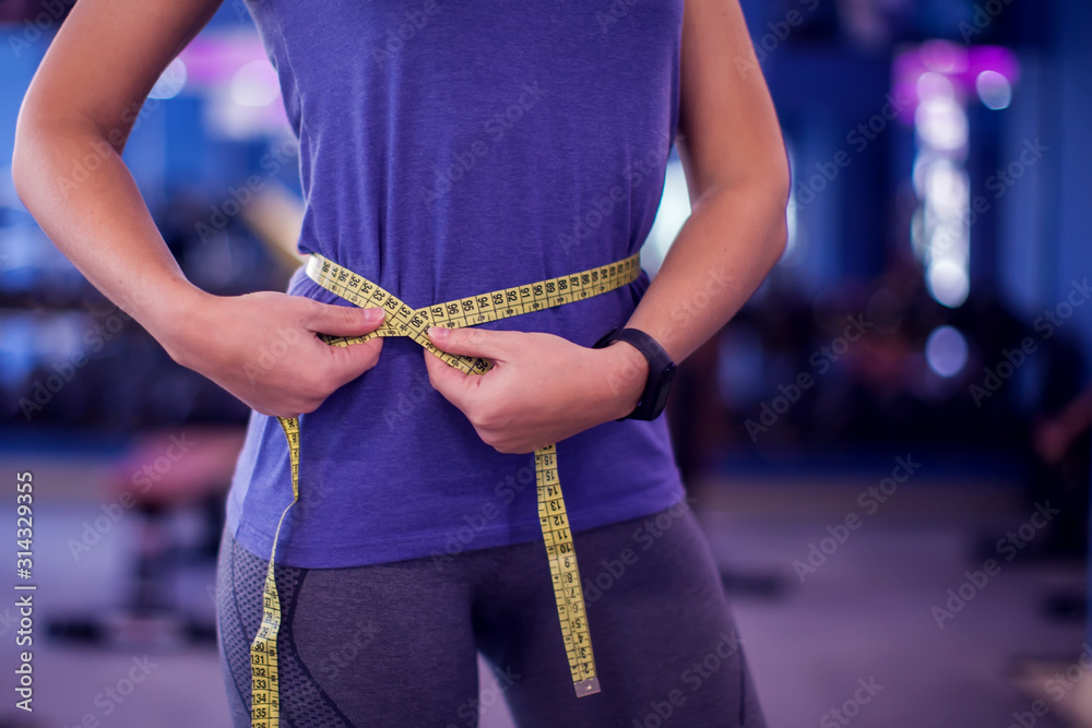 Woman measuring waist with meter in the gym. People, fitness and health ...