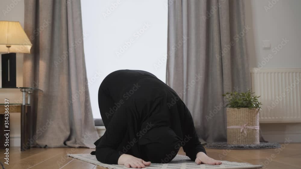 Young Muslim lady in black traditional hijab bowing down and raising up ...