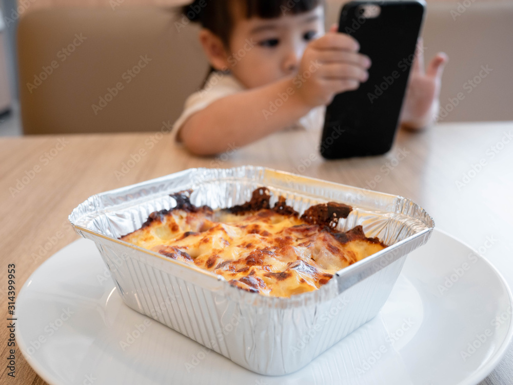 Little Asian child girl eating lunch while watching cartoon on the ...