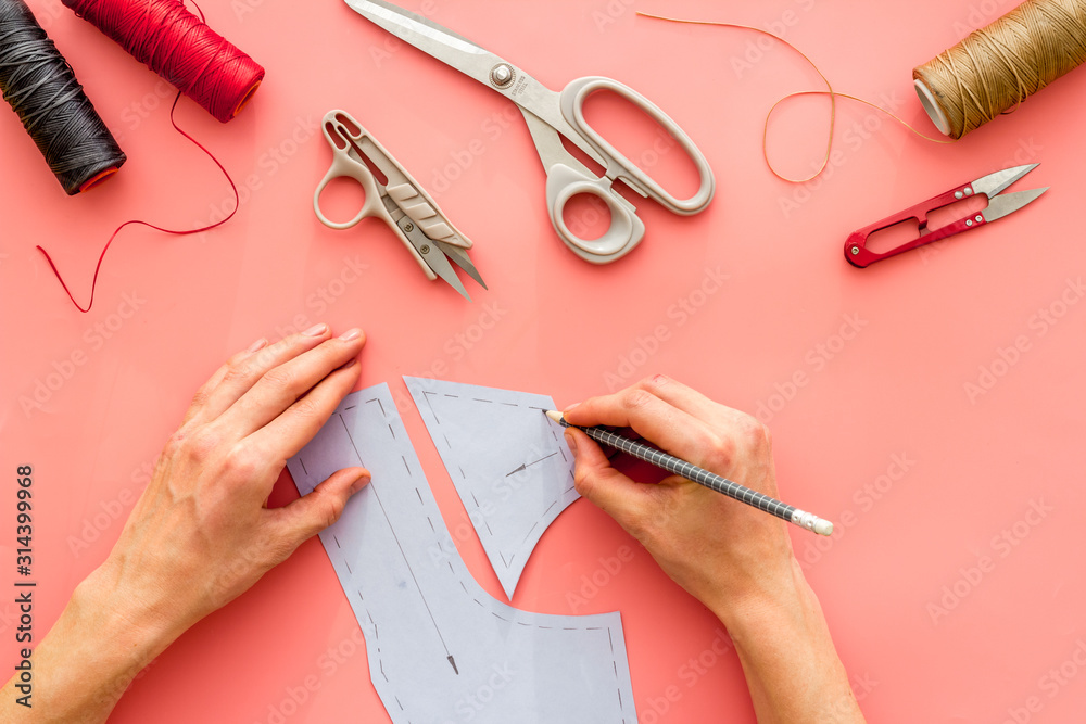 Tailor working. Women hands drawing patterns for clothes on pink ...
