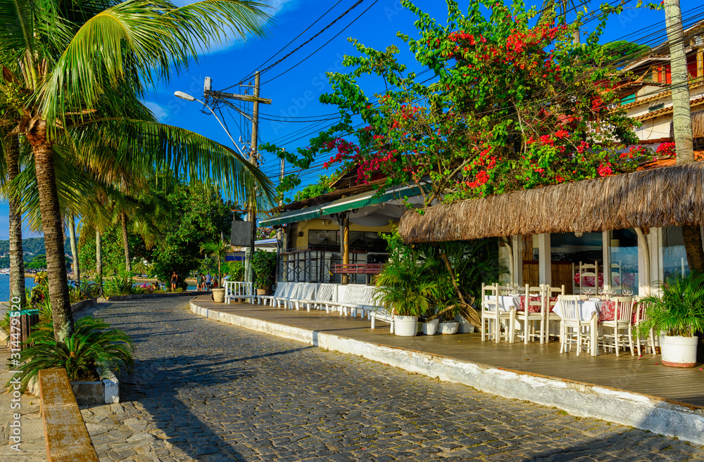 Seafront of Brigitte Bardot with palms and tables of restaurant in ...