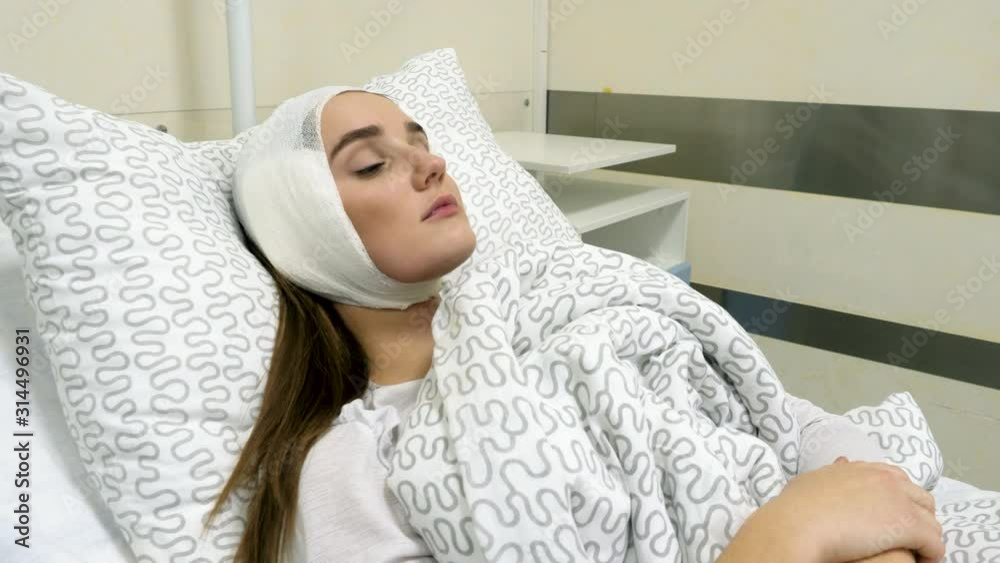 Plastic surgery. Closeup of young sad woman with bandaged head lying in ...
